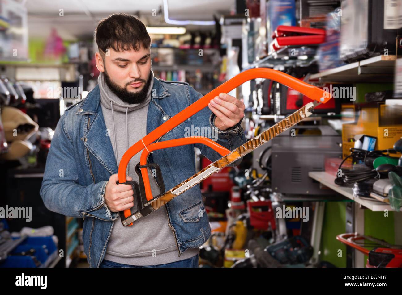 Portrait adult male with hacksaw in tools store Stock Photo - Alamy