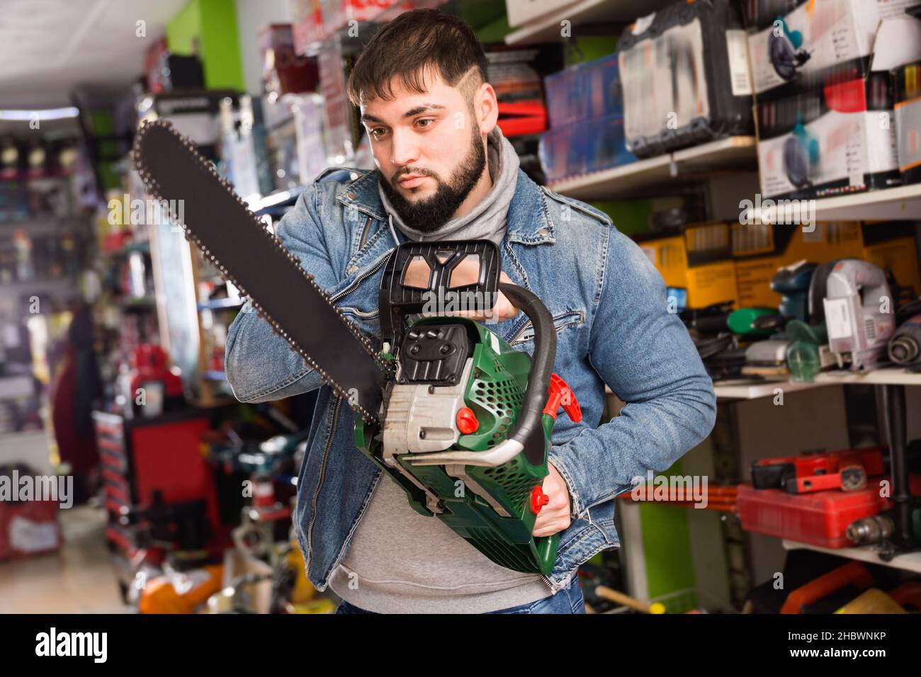Positive consumer chooses chainsaw in a tool store Stock Photo - Alamy