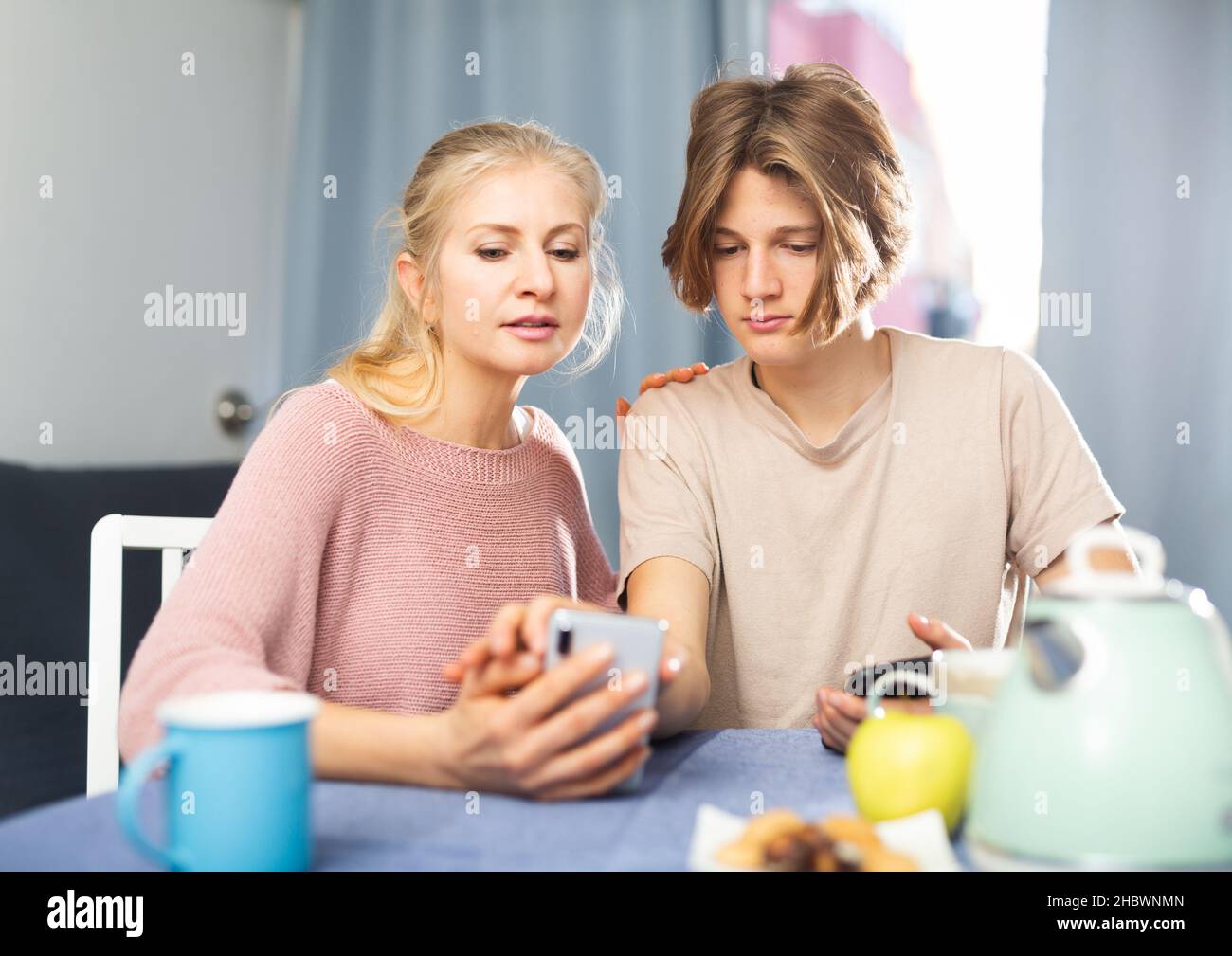 Mother and son using phones during breakfast Stock Photo - Alamy