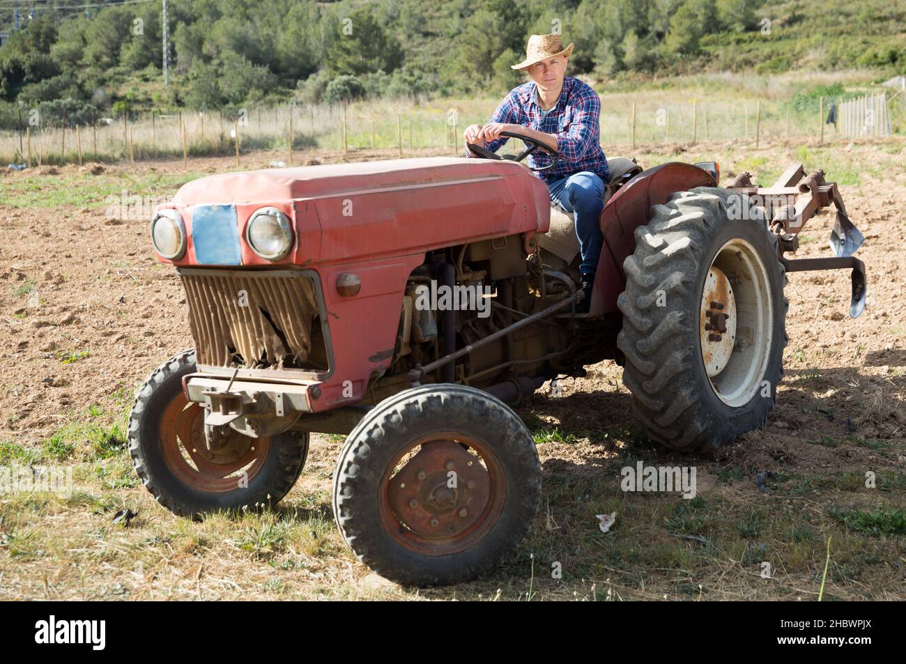 Positive man working on farm tractor Stock Photo - Alamy