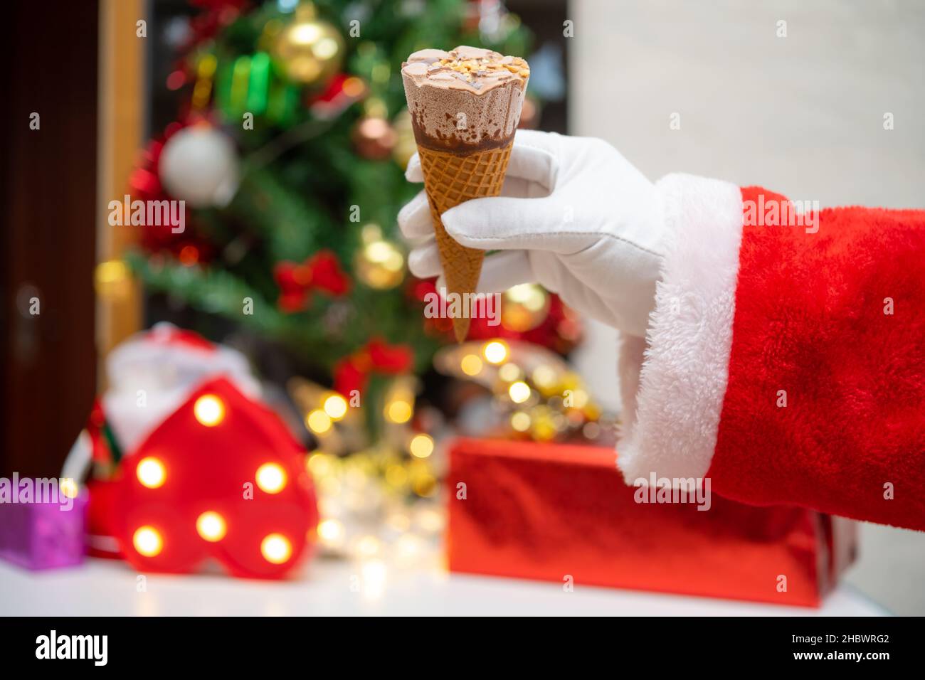 Santa Claus holding an ice cream cone in front of Christmas decorations ...
