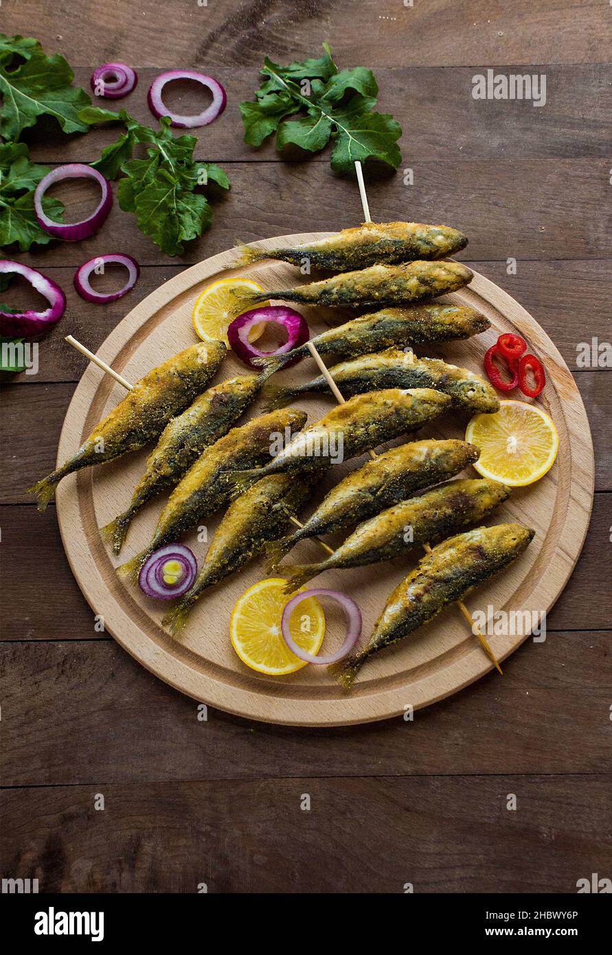Fried horse mackerel,istavrit fish skewered wooden sticks designed on ...