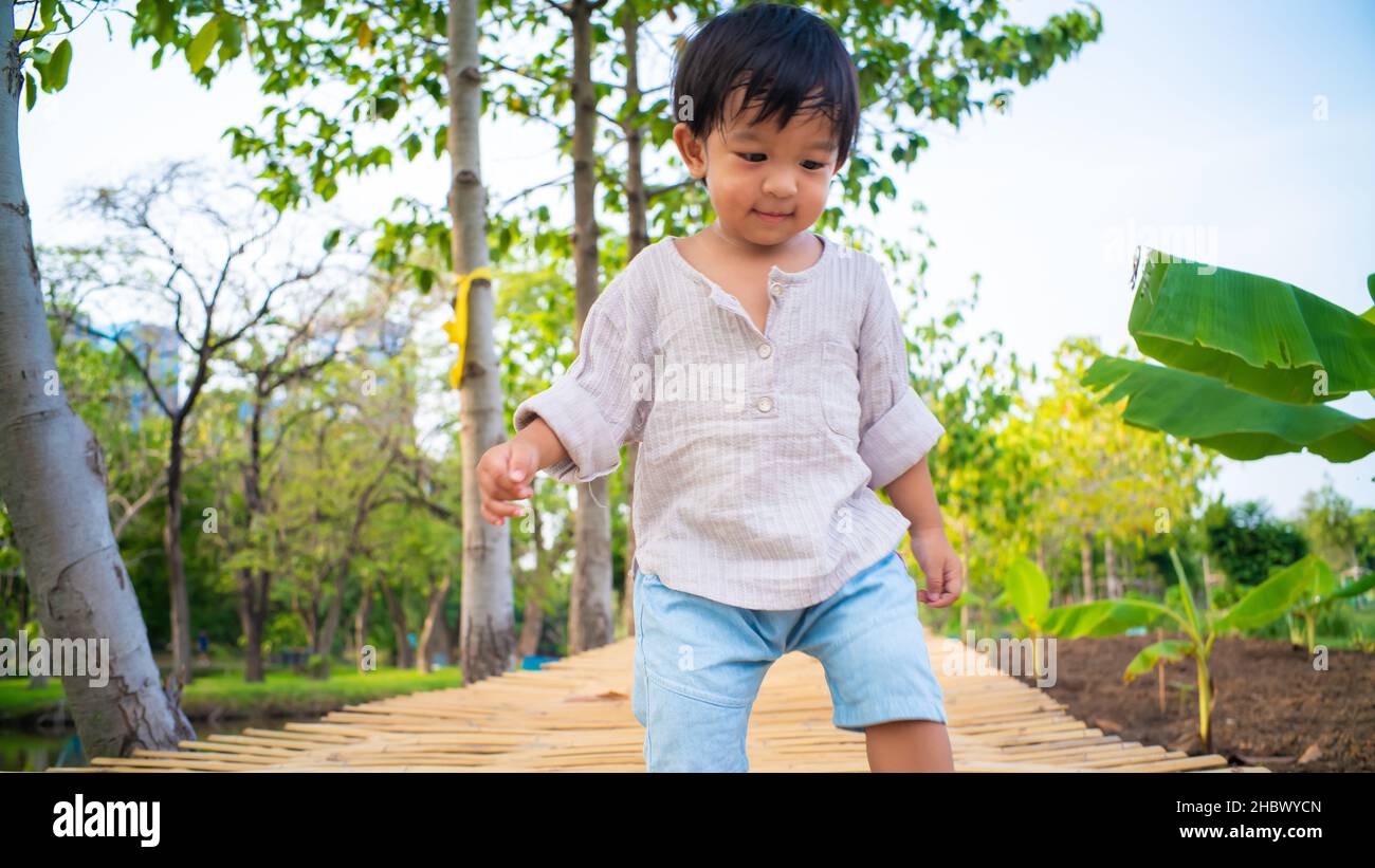 Little toddler boy walking outdoor city park with tree nature learnning ...