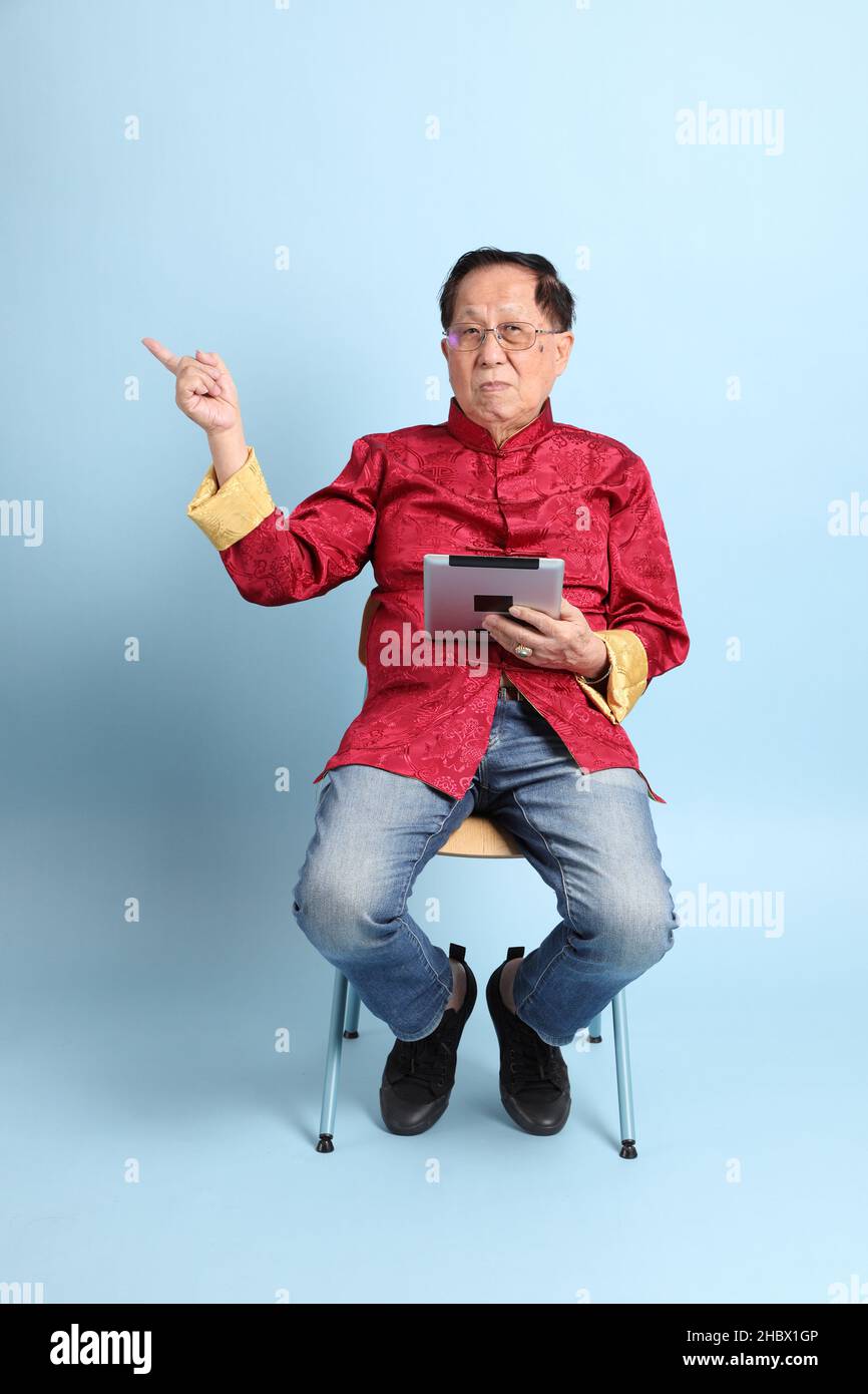 The senior Asian man wearing traditional Chinese shirt sitting on the ...