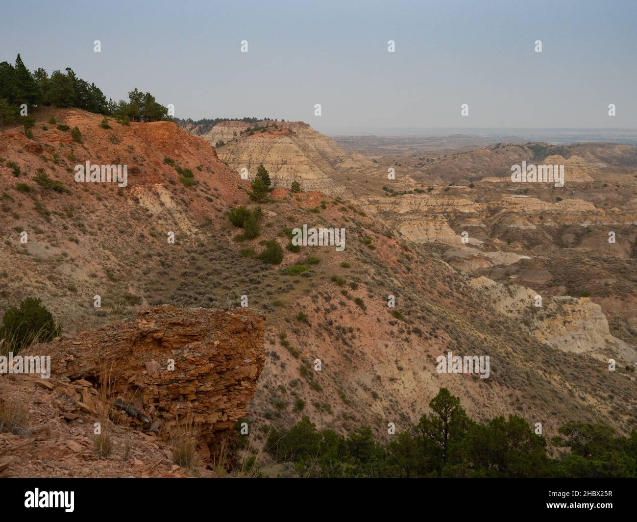 Orange shale rock formation in foreground and yellow, striped mounds of ...