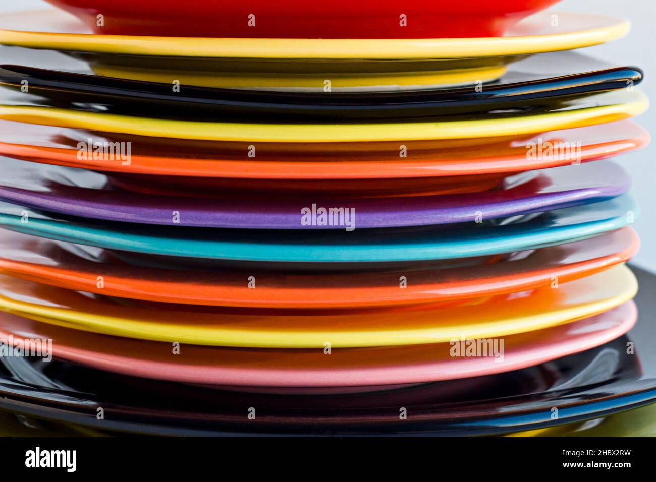 Close-up taken of colorful,clean dinner plates stacked on white surface ...