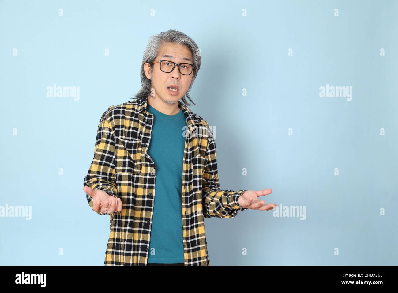 The senior Asian man with yellow plaid shirt standing on the blue ...