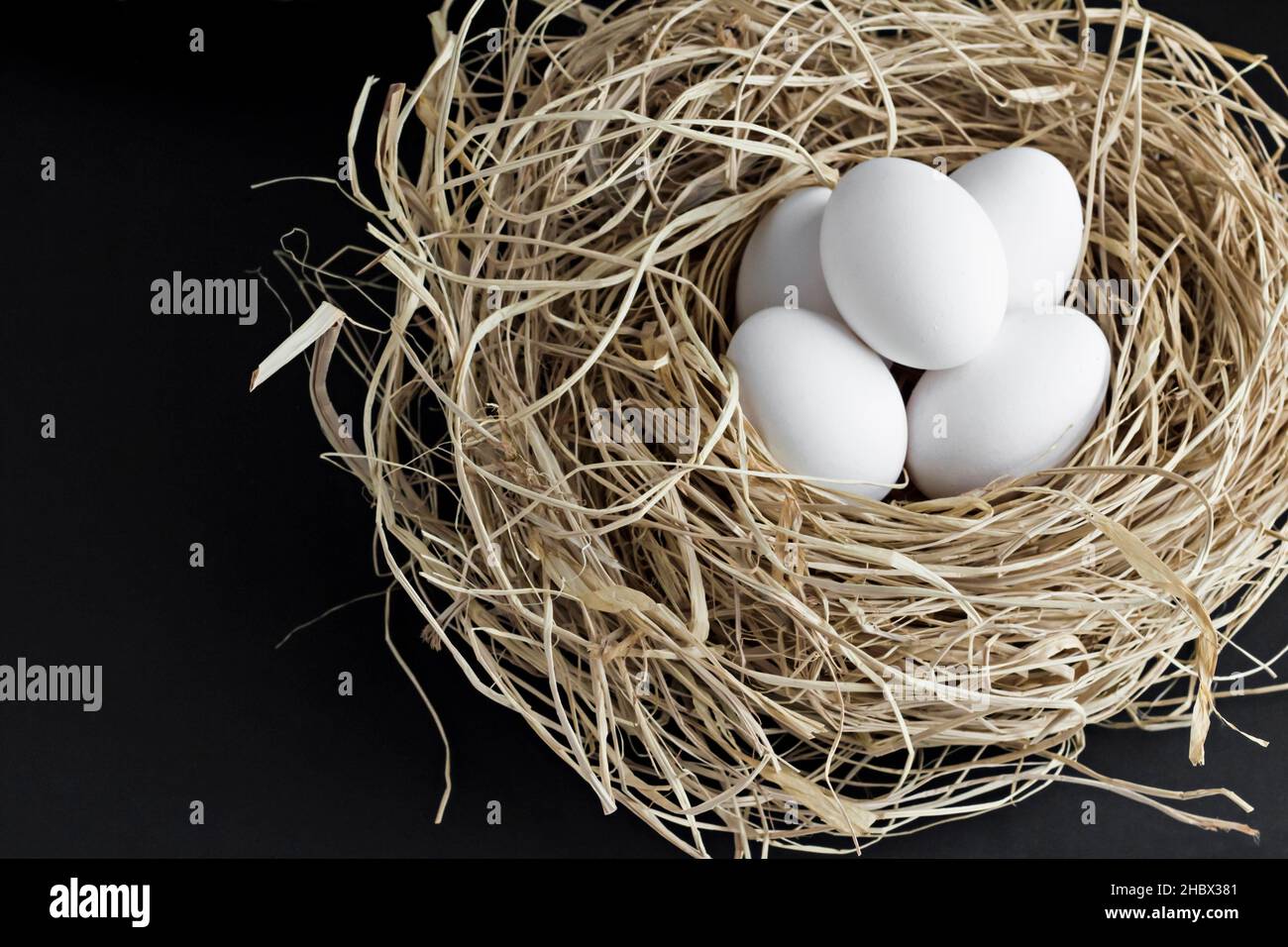 Fresh white eggs in the natural nesting box on the black surface ...