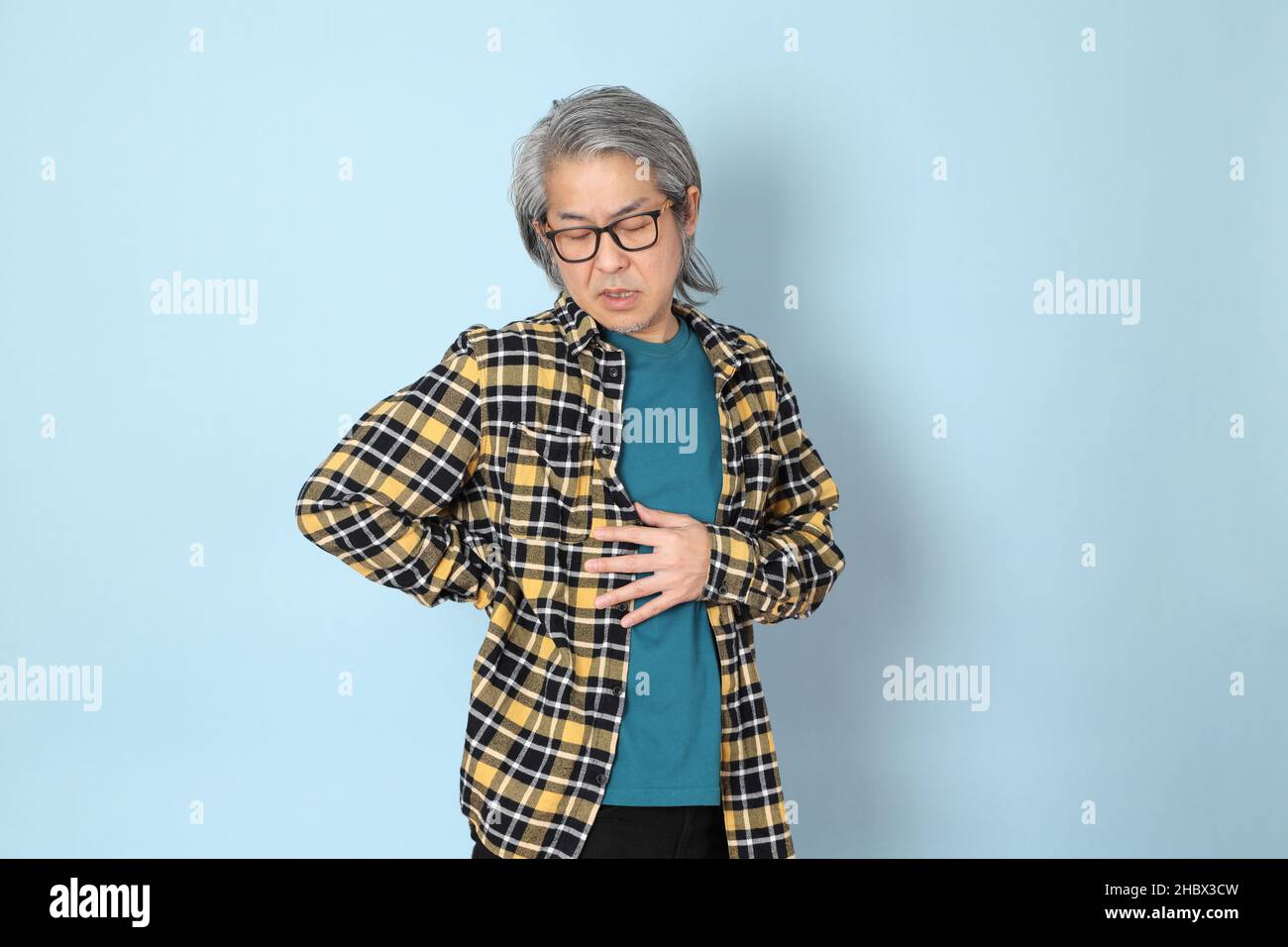The senior Asian man with yellow plaid shirt standing on the blue ...