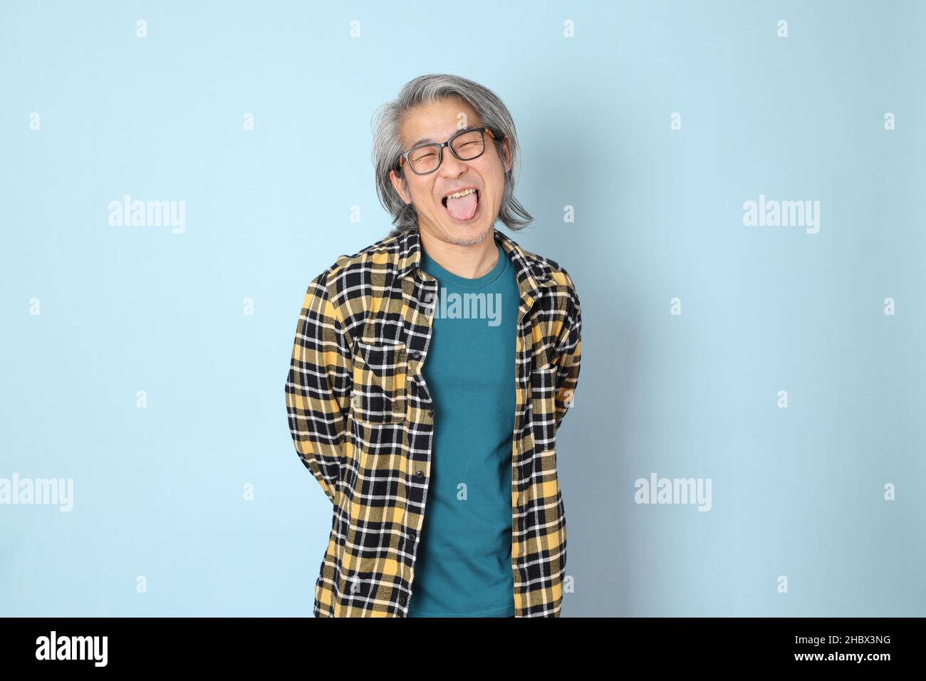 The senior Asian man with yellow plaid shirt standing on the blue ...