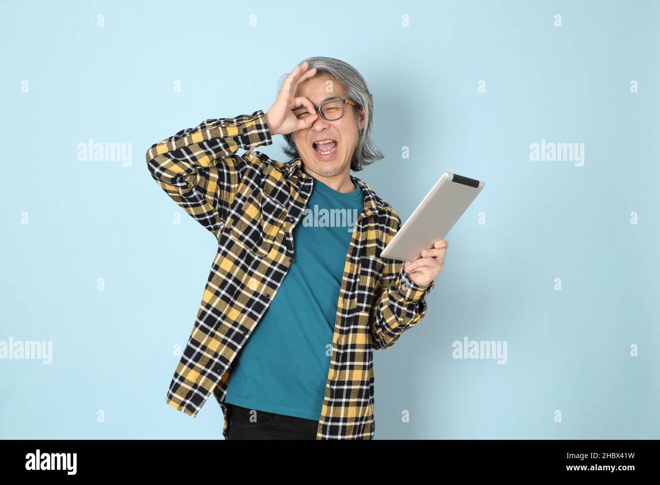 The senior Asian man with yellow plaid shirt standing on the blue ...