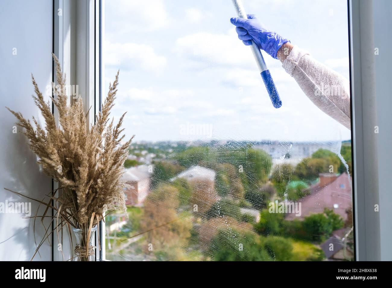 Employee hand in rubber protective glove cleans window with foam and ...