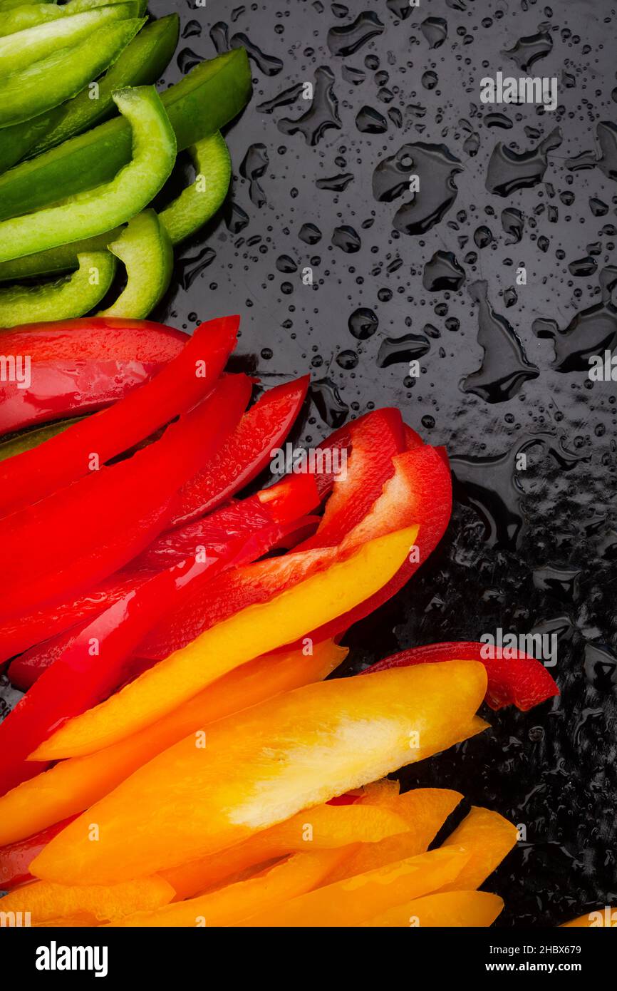 Fresh Three colored bell peppers julienne cut on black surface Stock ...