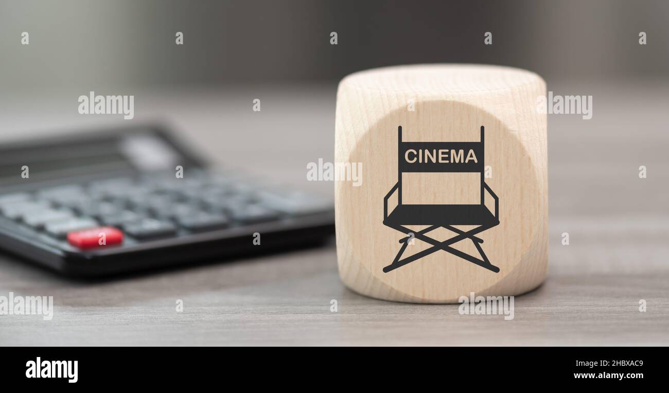 Wooden block with symbol of cinema concept and calculator on background ...