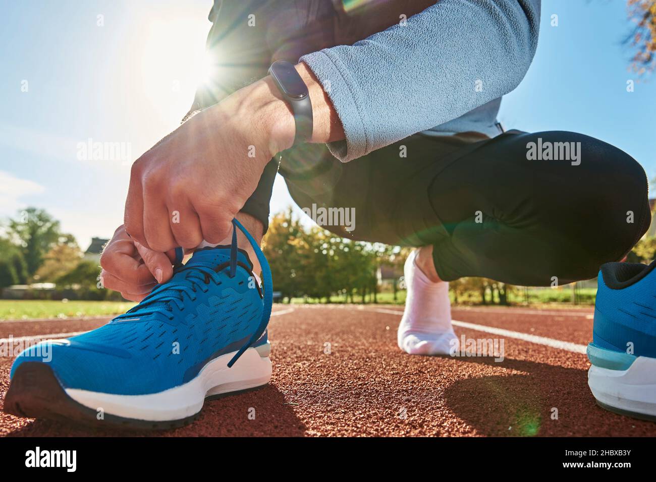 Male runner in blue sneakers get ready for run at stadium track, close ...