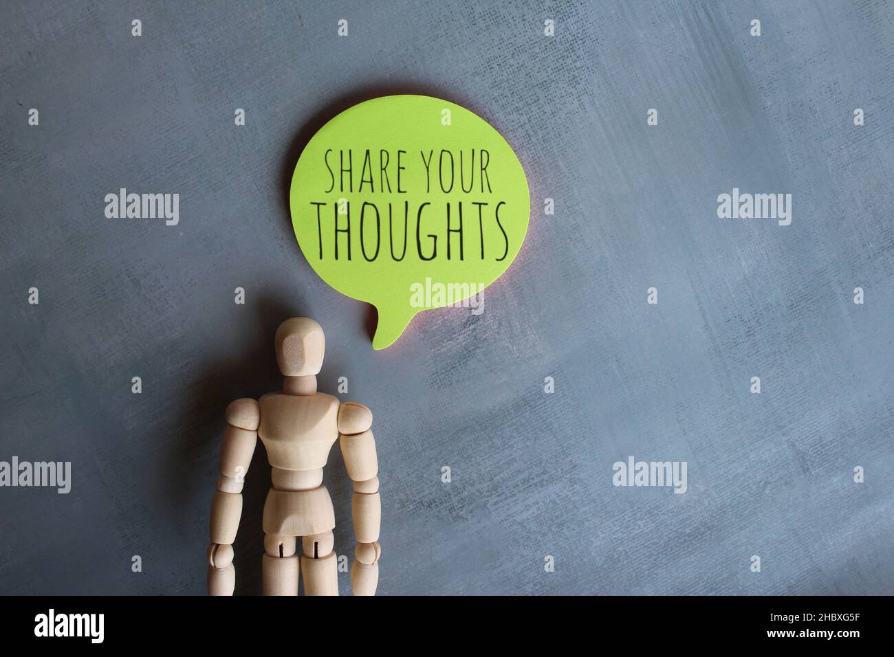 Wooden human figure and speech bubble with text SHARE YOUR THOUGHTS ...