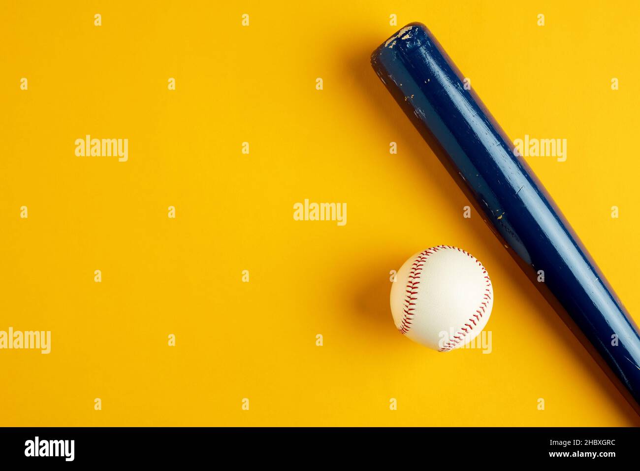 Blue wooden baseball bat and a baseball ball on yellow background with ...