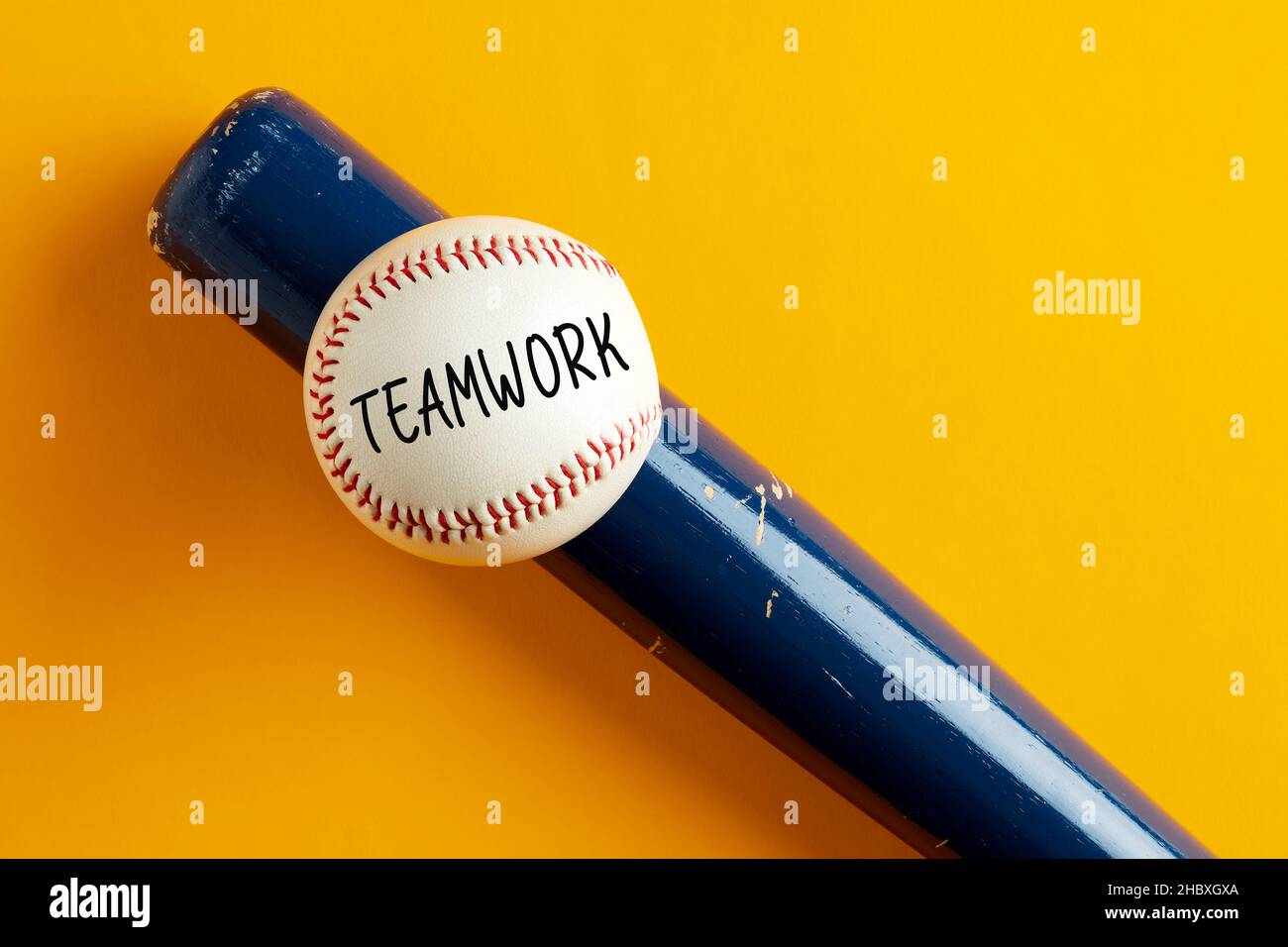 Baseball ball on a bat on yellow background with the word teamwork ...