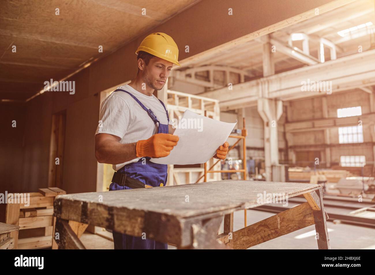 Serious man builder studying architectural plan at construction site ...