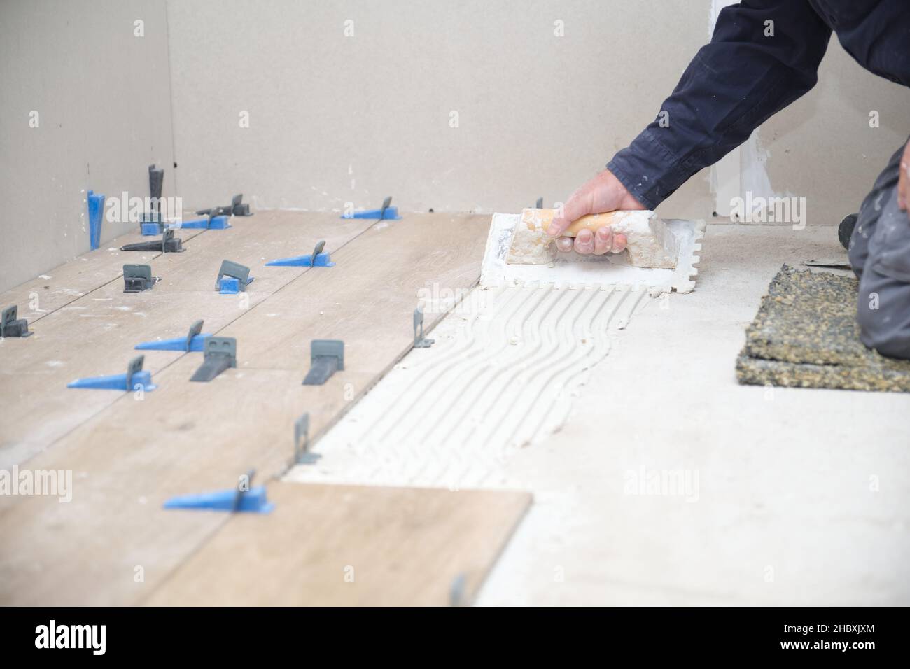 Worker hands putting tiles adhesive to the floor with the notched ...