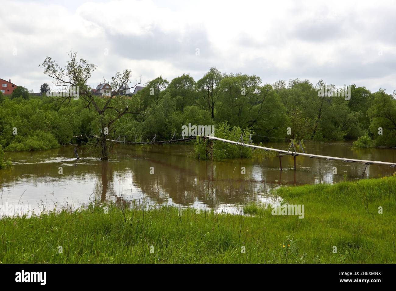 Rustic suspension footbridge across the river during flood after rains ...