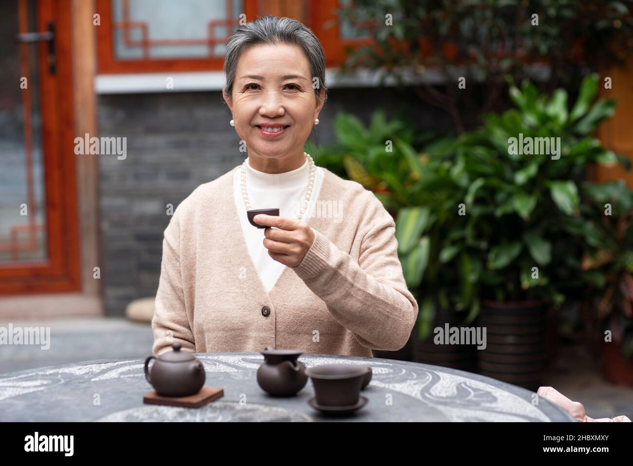 Old woman drinking tea in the courtyard Stock Photo - Alamy