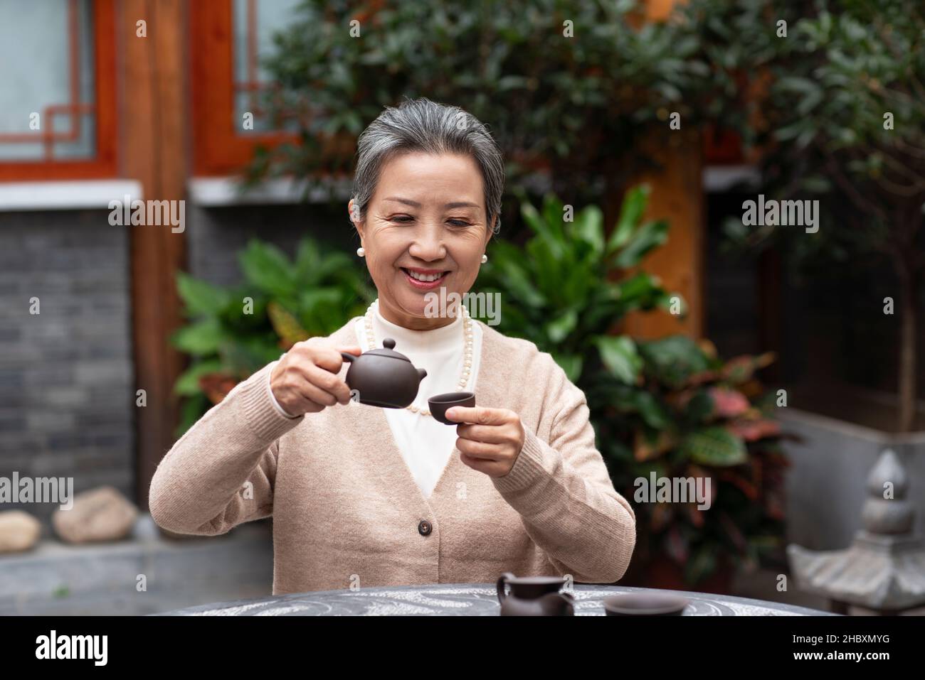 Old woman drinking tea in the courtyard Stock Photo - Alamy