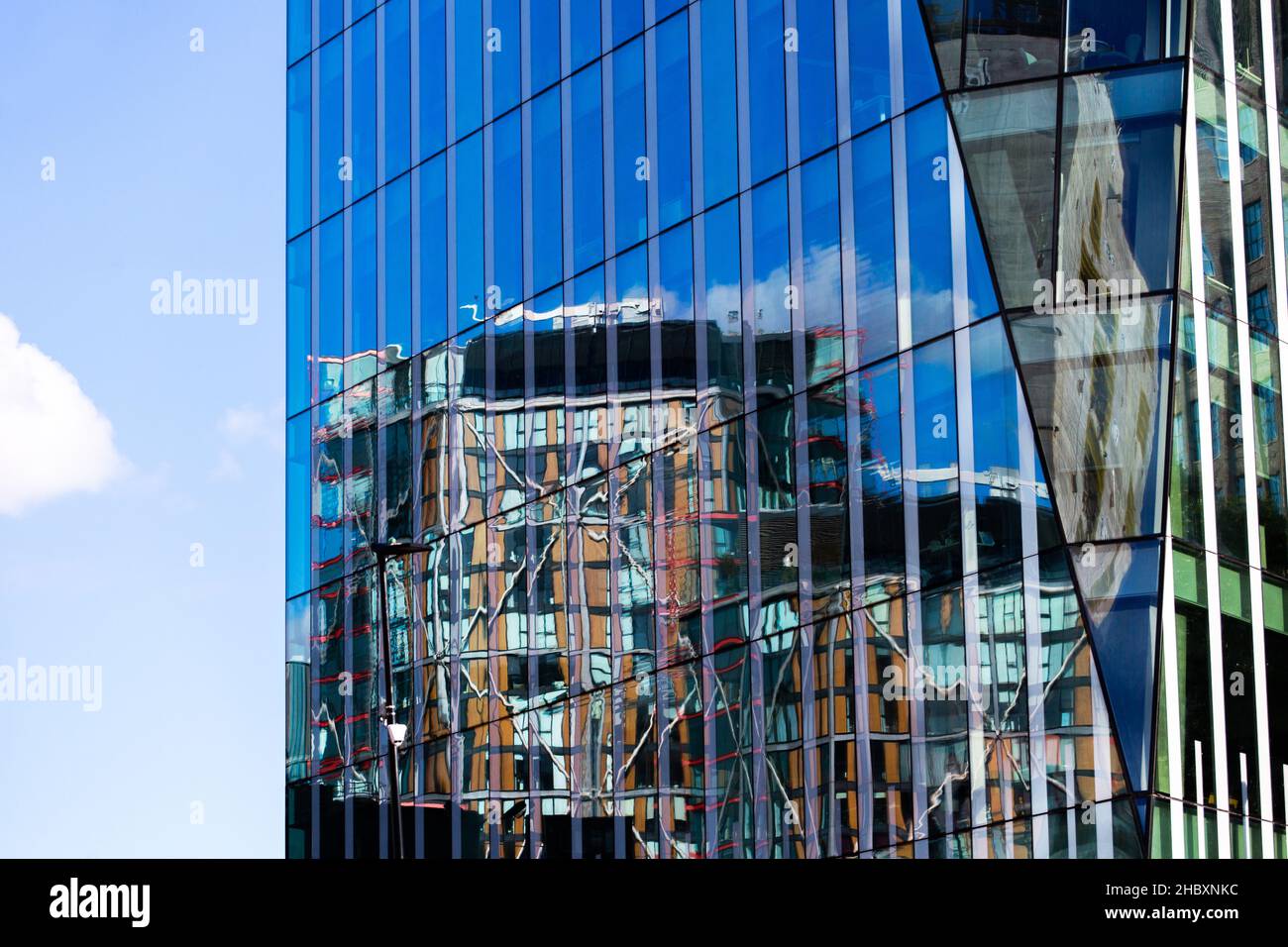 London city buildings and blue sky reflected in large glass building ...