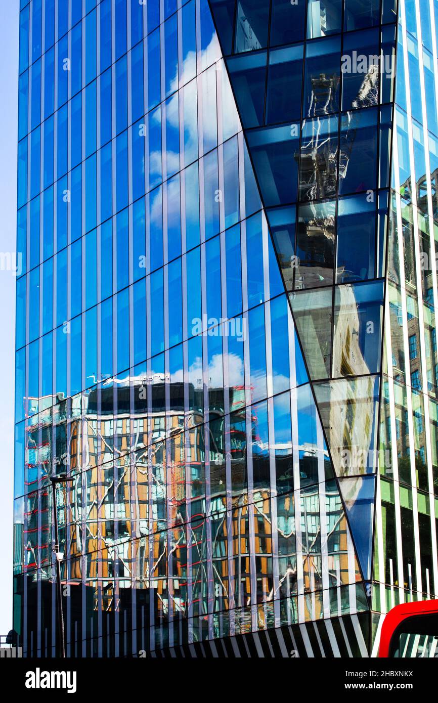 London city buildings and blue sky reflected in large glass building ...