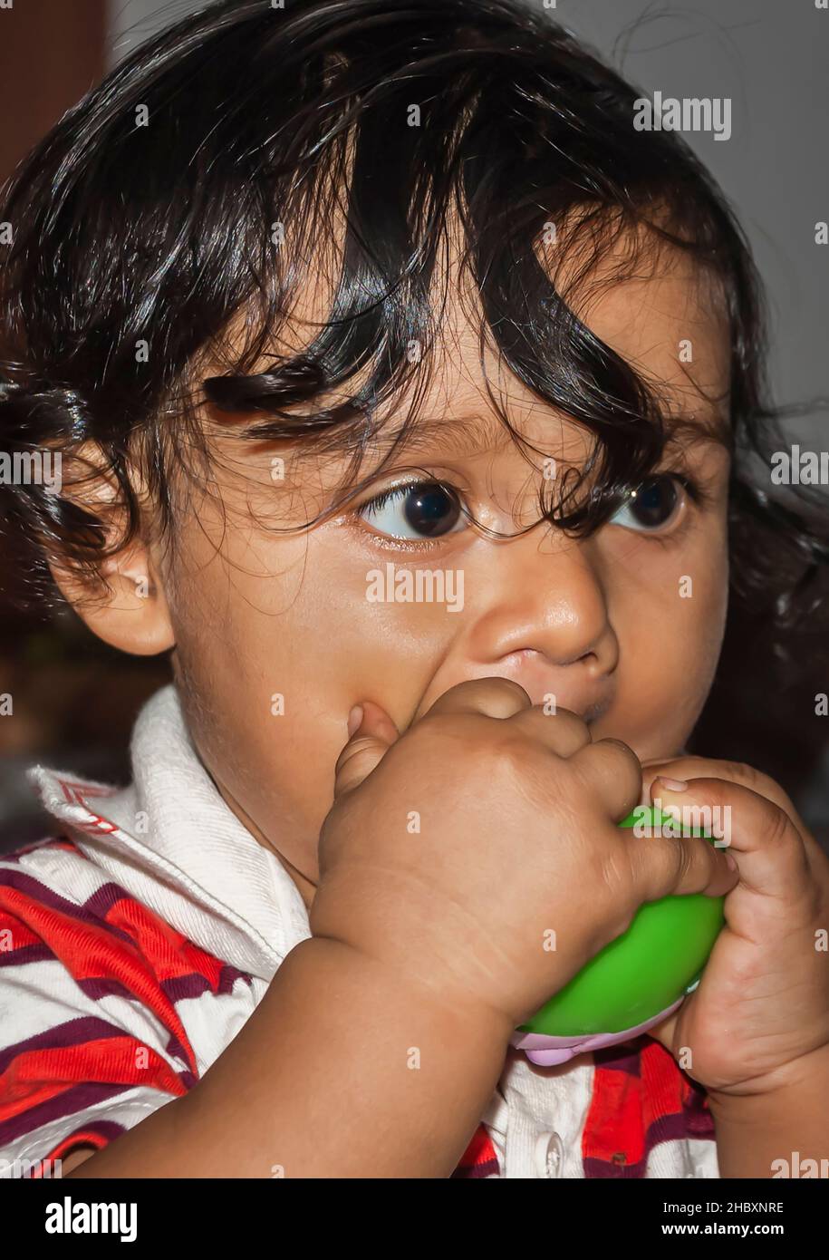 An East Indian baby boy showing signs of teething by chewing on a ...