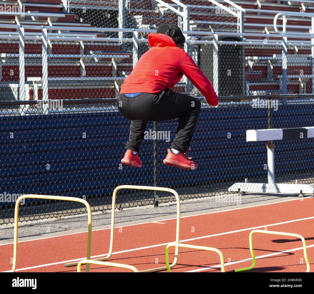 Rear view of high school athlete jumping high over plastic yellow ...