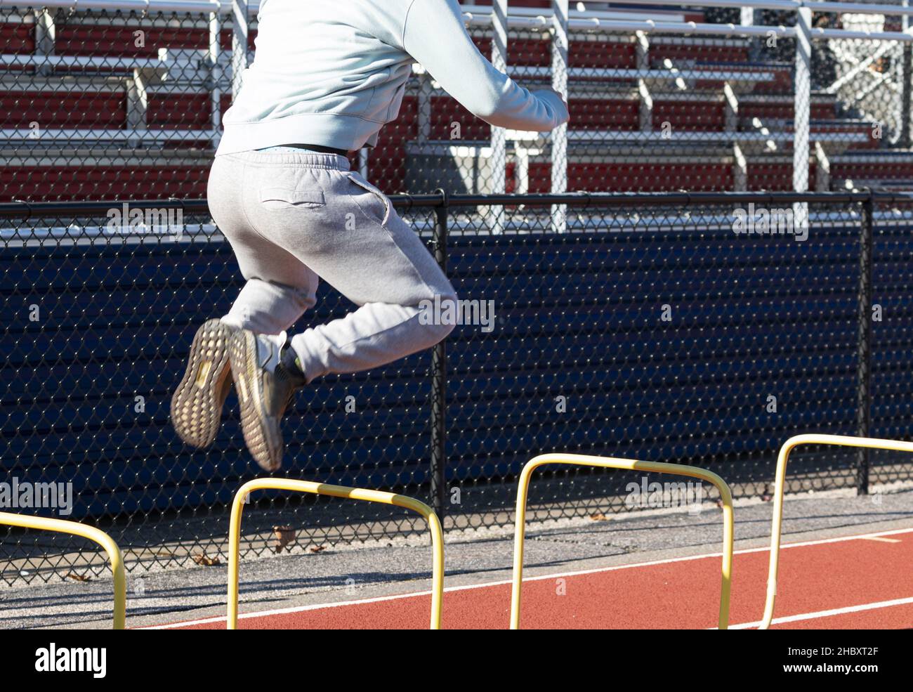 Side view of a high school boy jumping over yellow two foot high ...