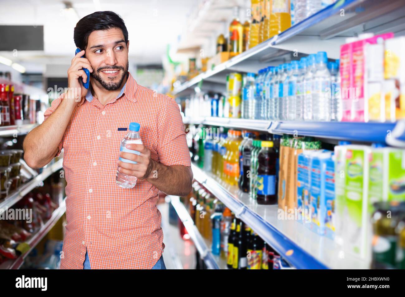 Man is choosing water with help mobile in supermarket Stock Photo - Alamy