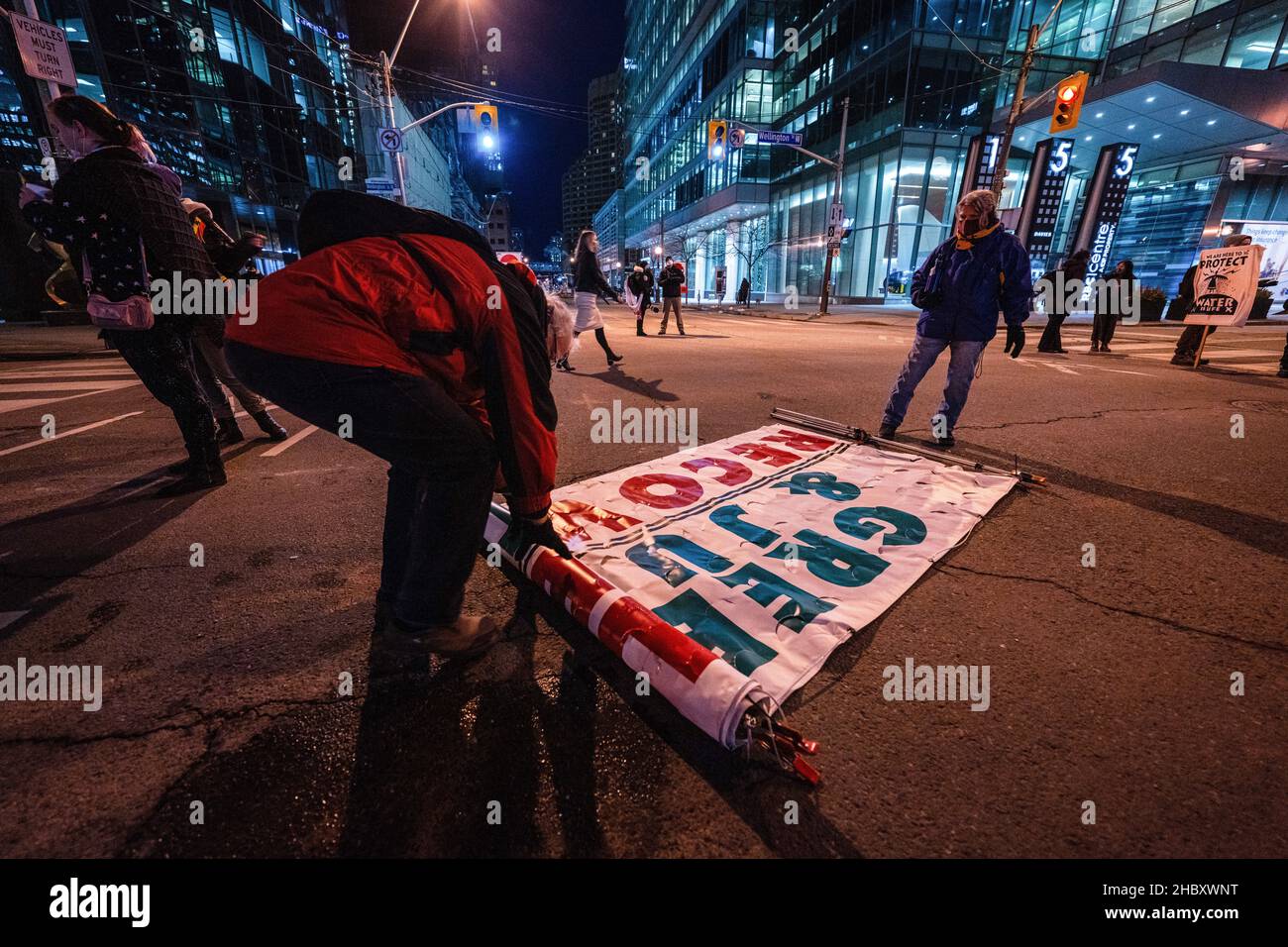Toronto, Canada. 21st Dec, 2021. An activist rolls up a banner during ...