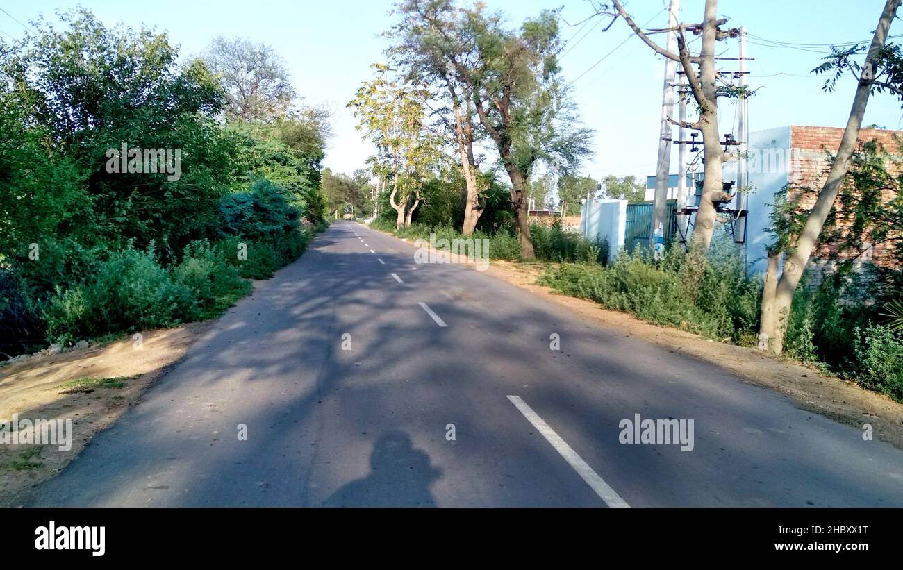 An empty rural black Peach Road with red soil road surrounded by green ...