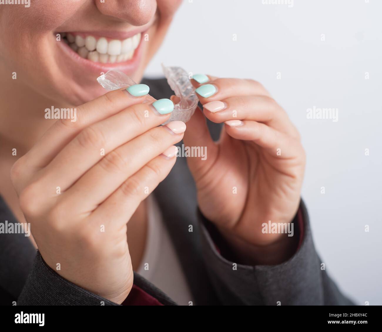 Close-up of a woman putting on transparent plastic retainers. The girl ...