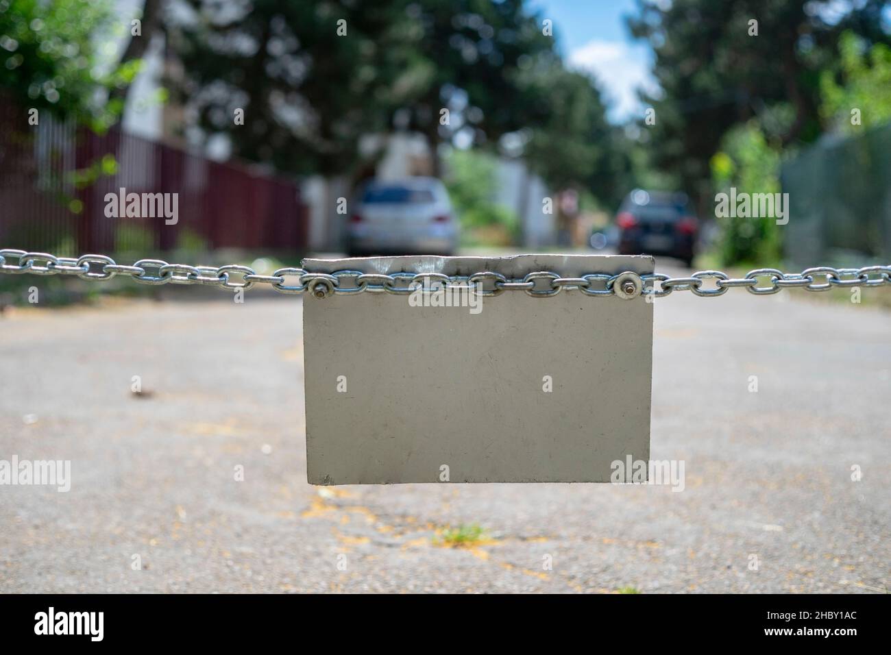 Empty metal sign, hanging on a chain, at the end of a road. Blurred ...