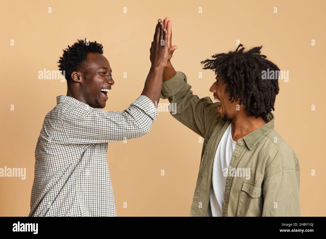 Two Joyful Black Guys Giving High Five To Each Other And Laughing Stock ...