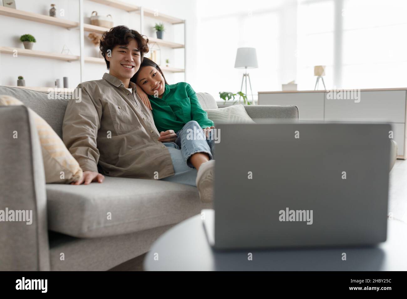 Millennial Asian couple watching movies on laptop computer online ...