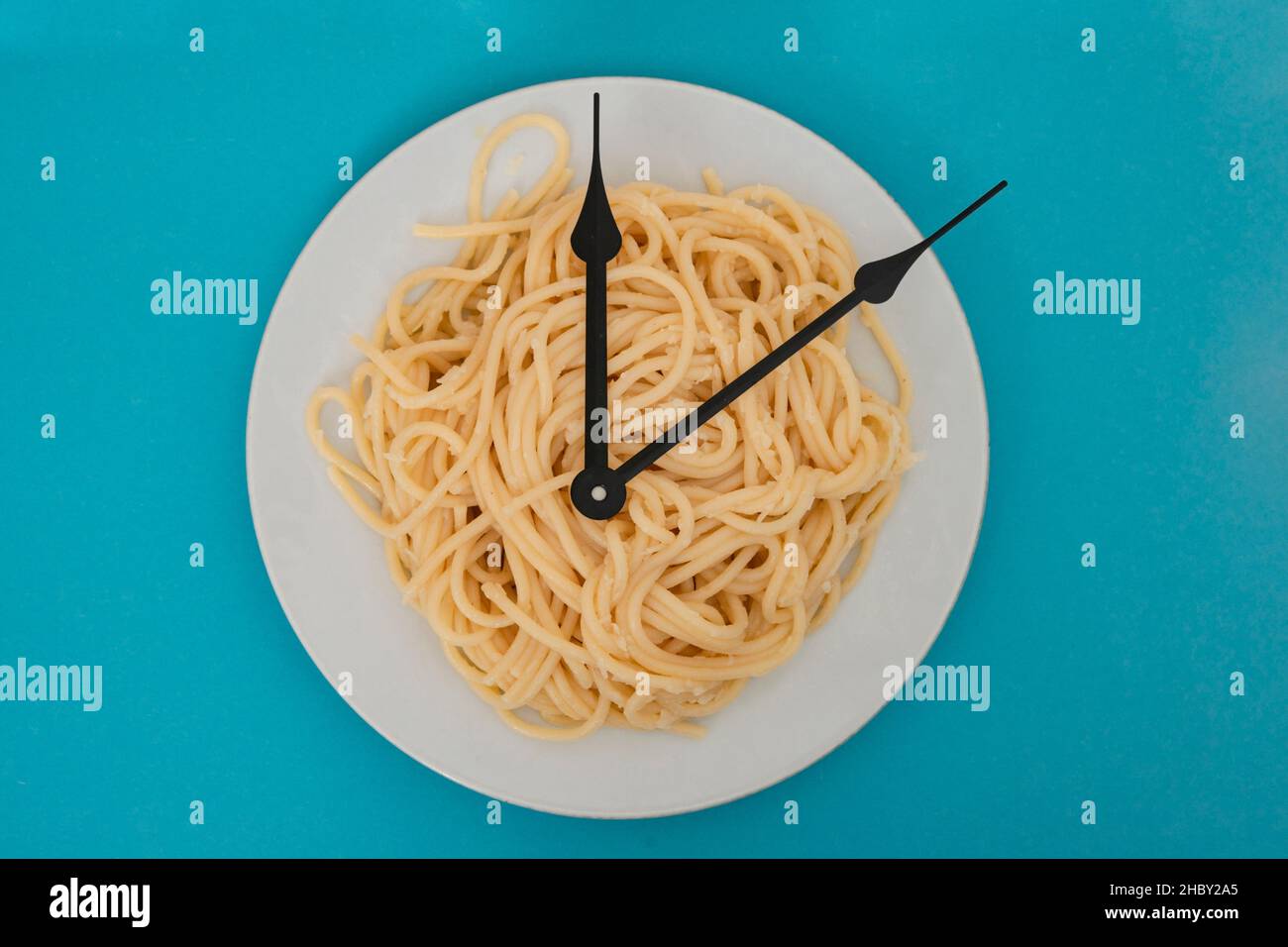 spaghetti on a white plate, on blue background, and clock tongues ...