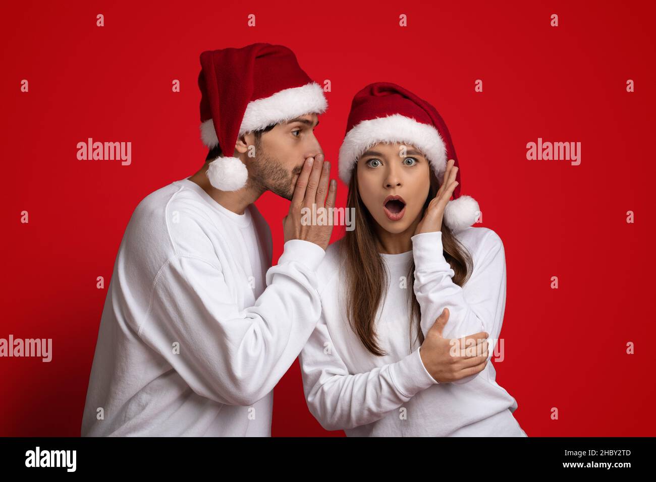 Mysterious Young Man In Santa Hat Sharing Secret With His Excited