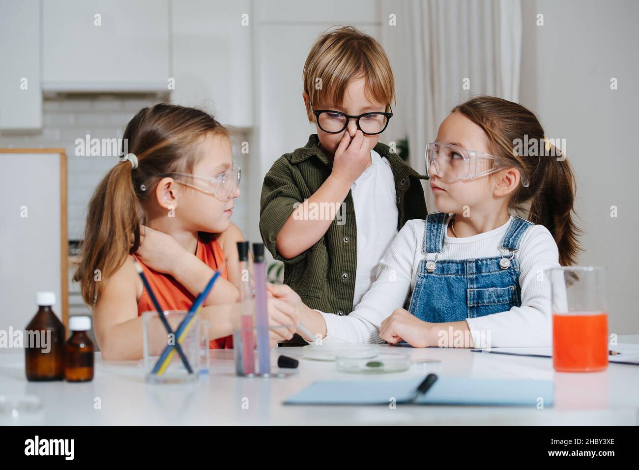 Funny little kids doing home science project, looking at each other in ...