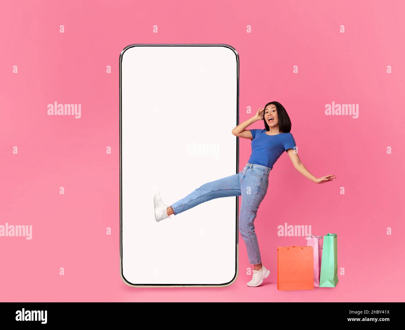 Excited Asian woman jumping near cell screen with shopping bags Stock ...