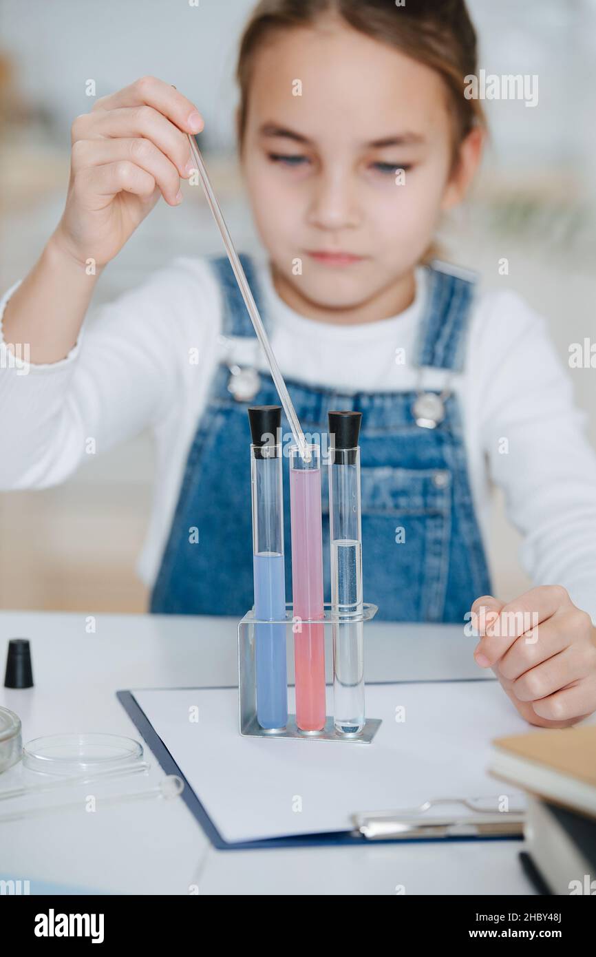 Blurred little girl doing home science project, filling a pipette with ...