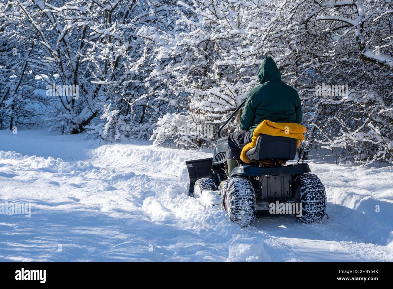 person in snow, man driving a snow plow tractor in a winter landscape ...