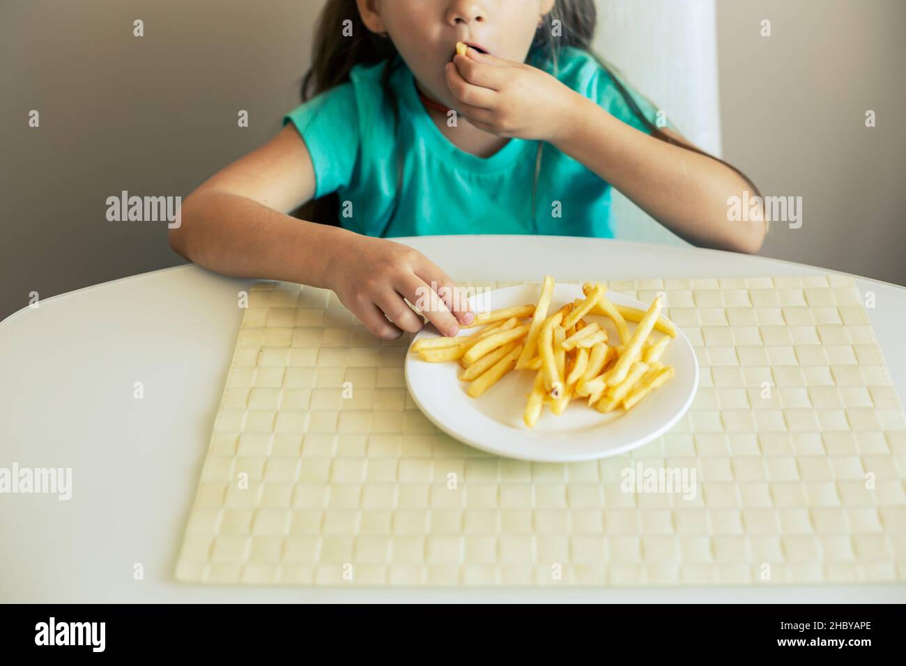 Close-up of a little girl eating French fries at the kitchen Stock ...