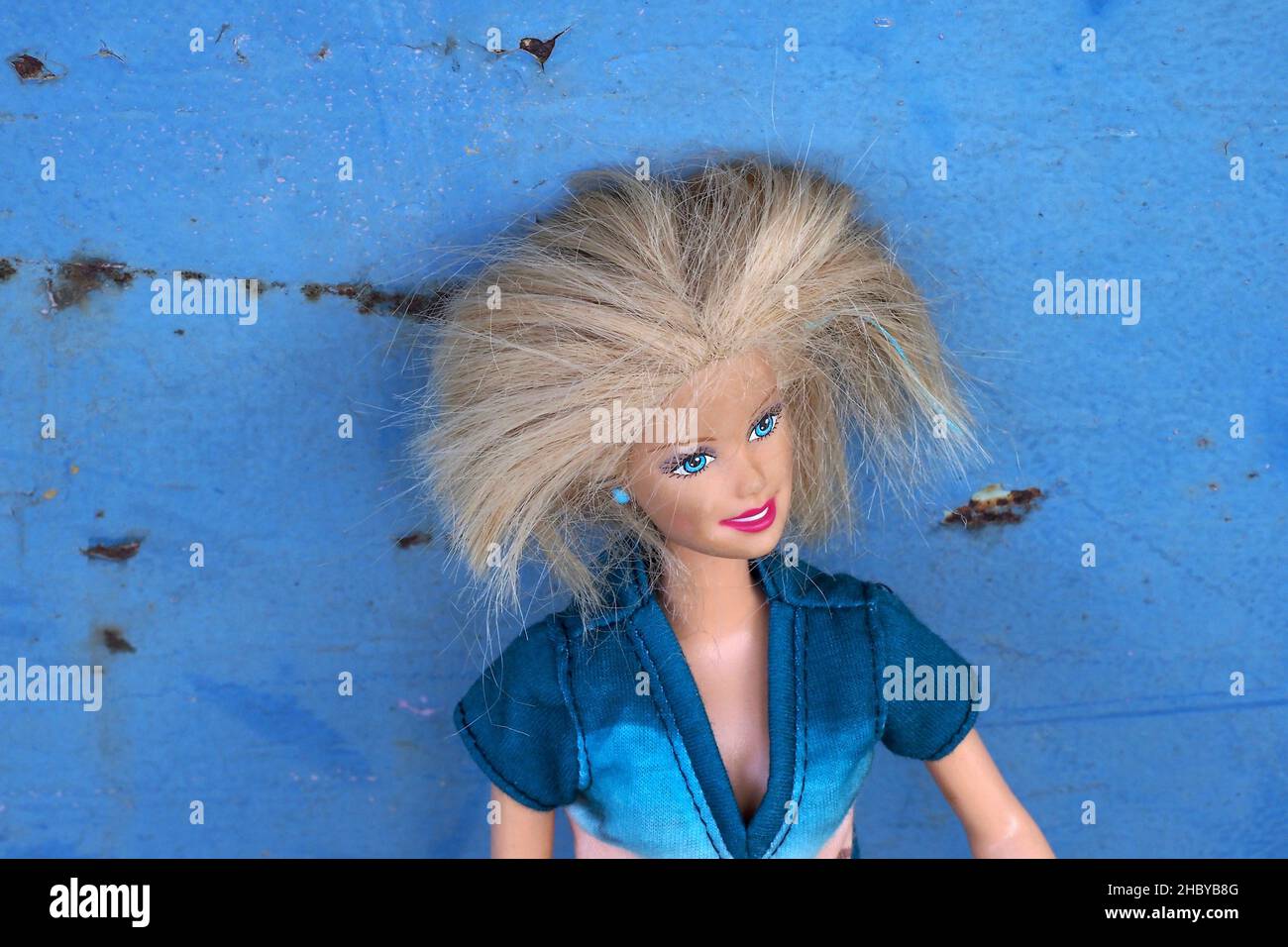 Barbie doll leaning against blue metal plate, from above Stock Photo ...