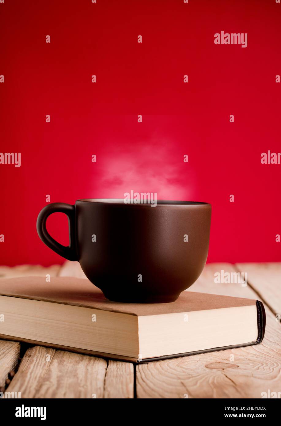Brown coffee cup with smoke on reading book, rustic wooden table, red ...