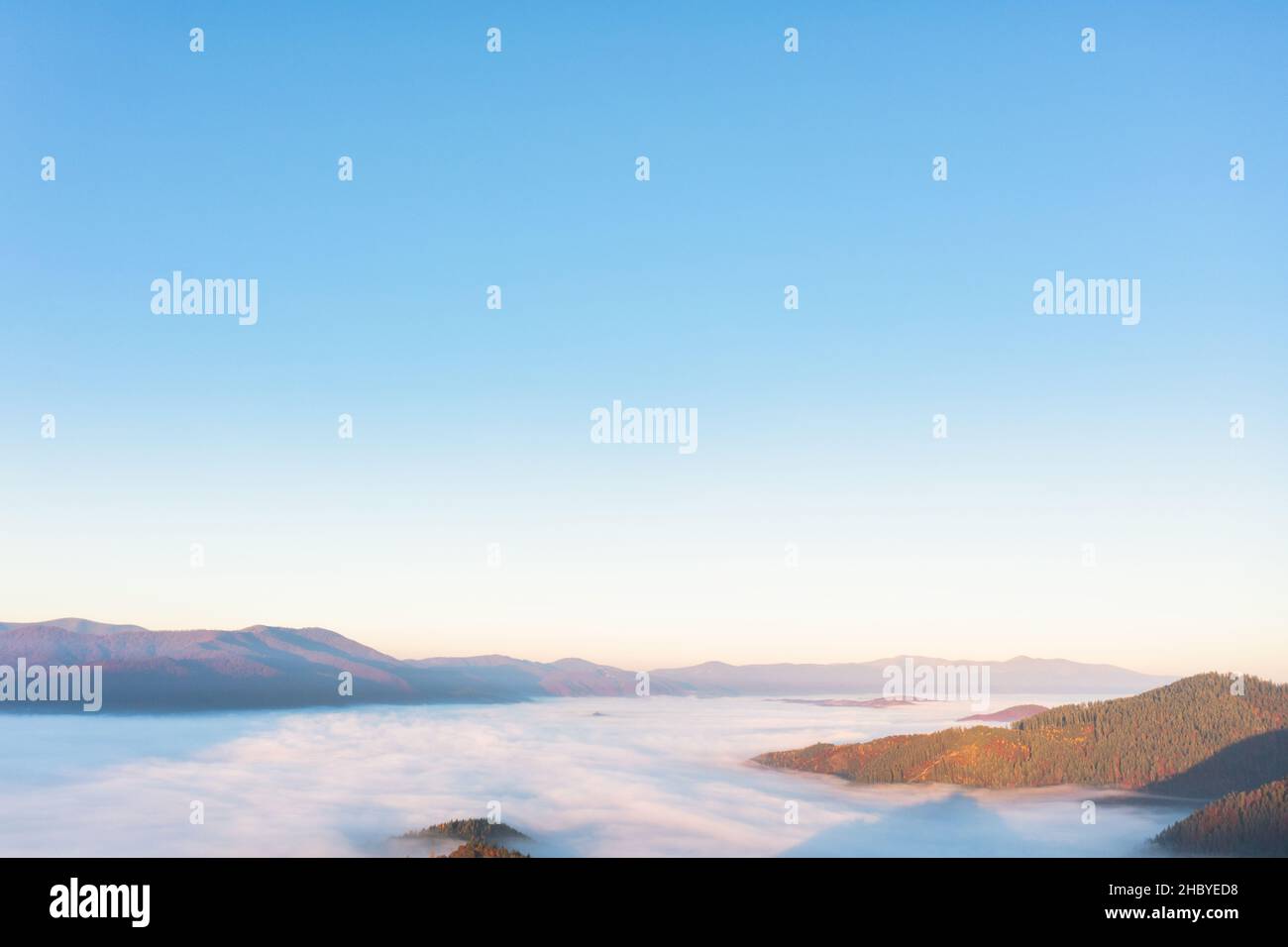 Thick layer of fog covering high mountains with terracotta and green ...