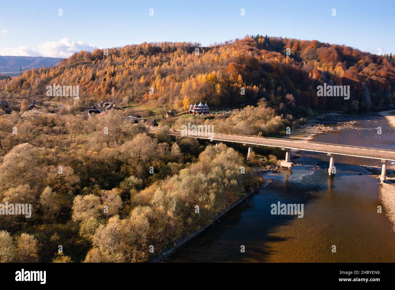 Bridge with asphalt road over narrow shallow river leading to ...